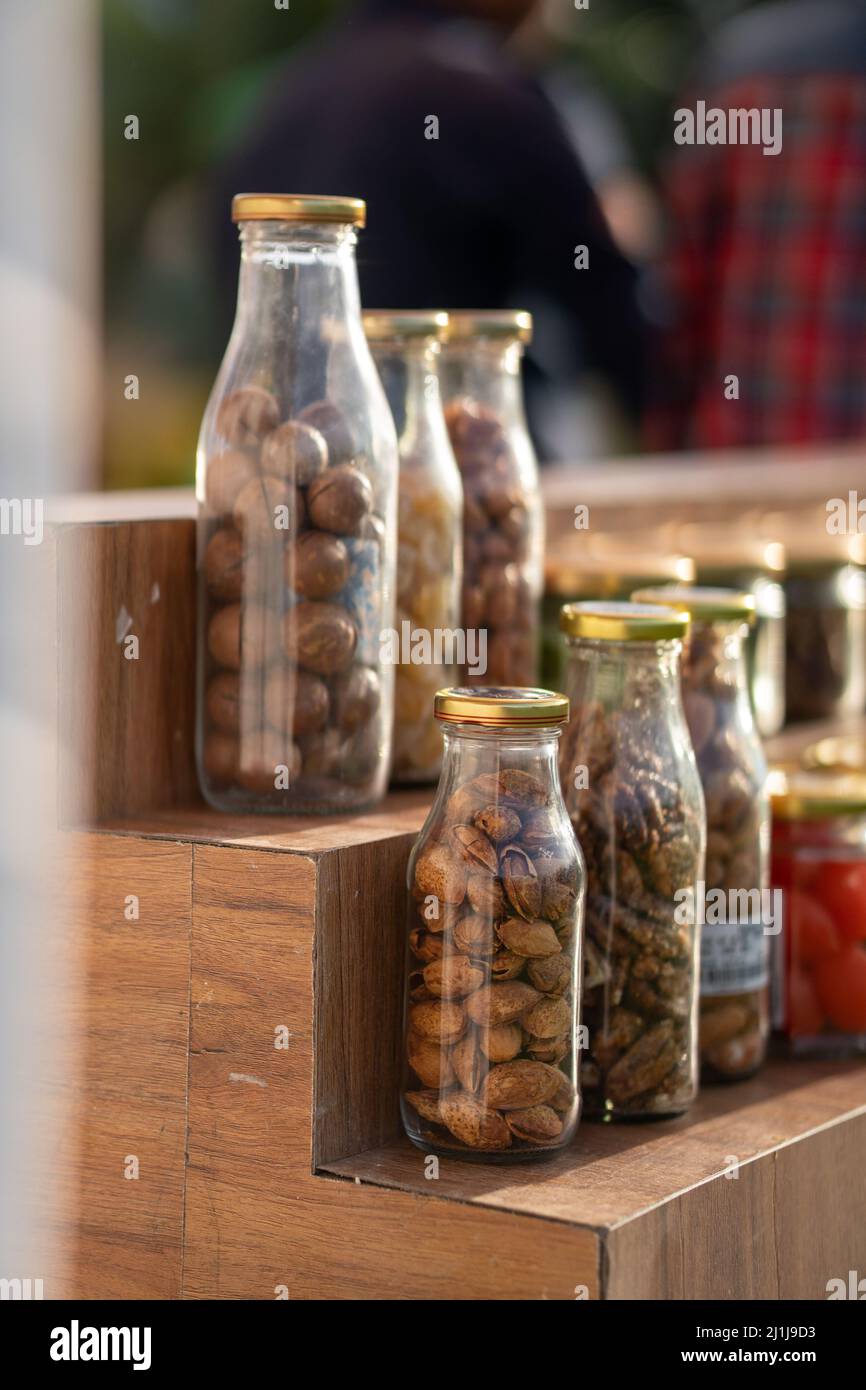 A vertical closeup shot different types of nuts in the glass bottles on ...