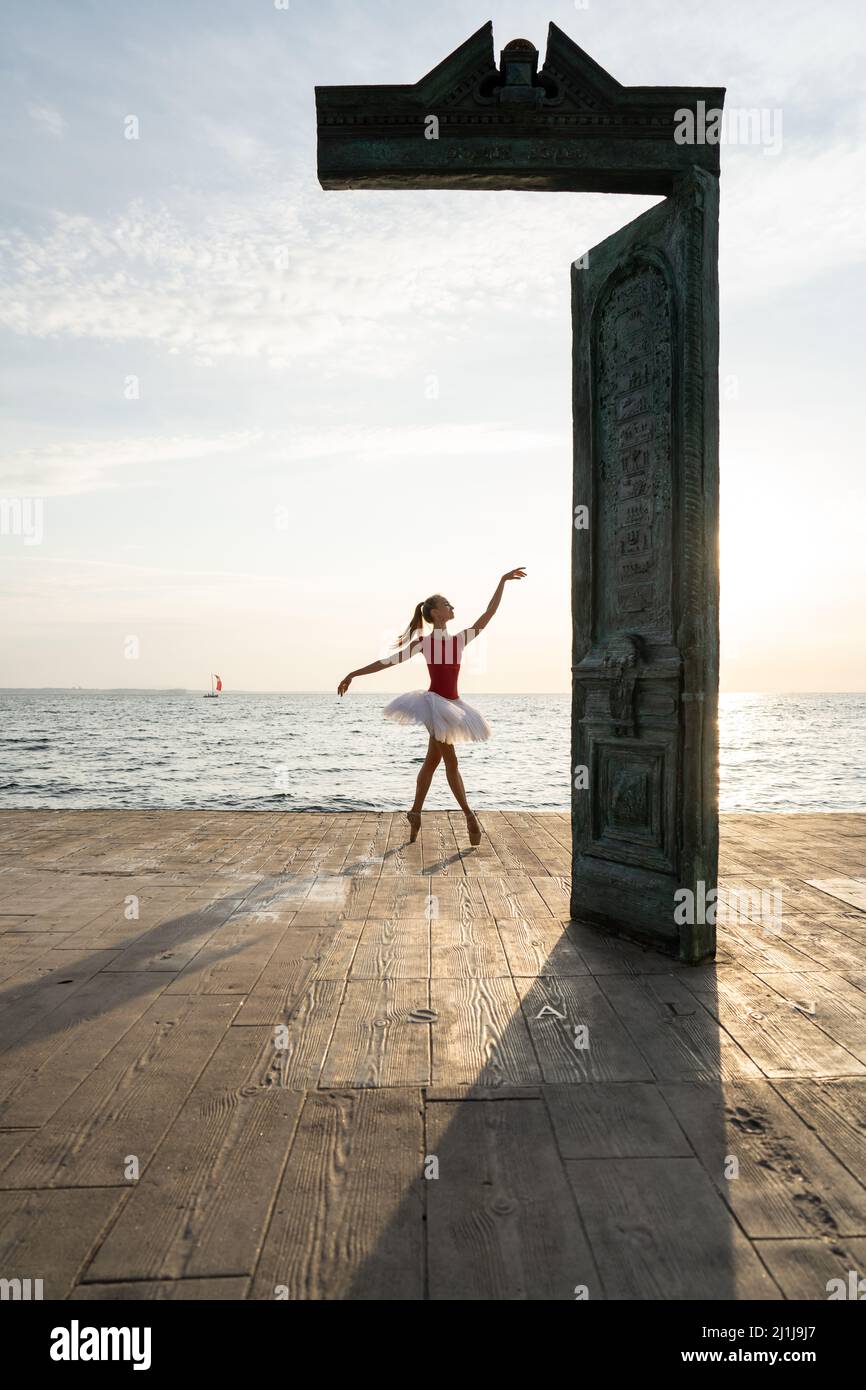 Female ballet dancer is posing near art object on seafront during ...