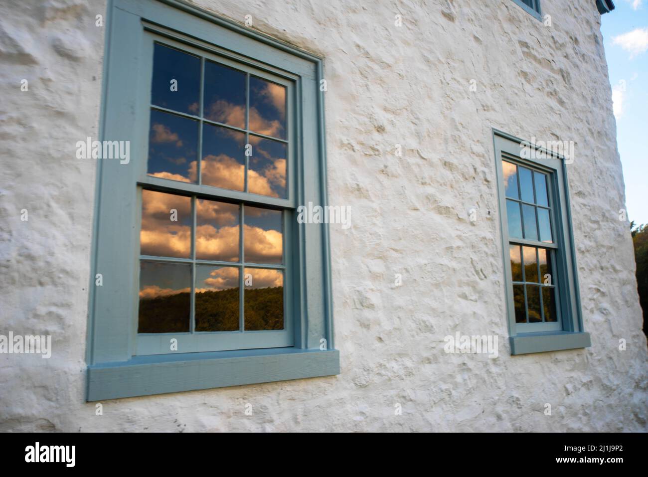 Clouds and blue sky reflected in 12-pane colonial white house windows ...