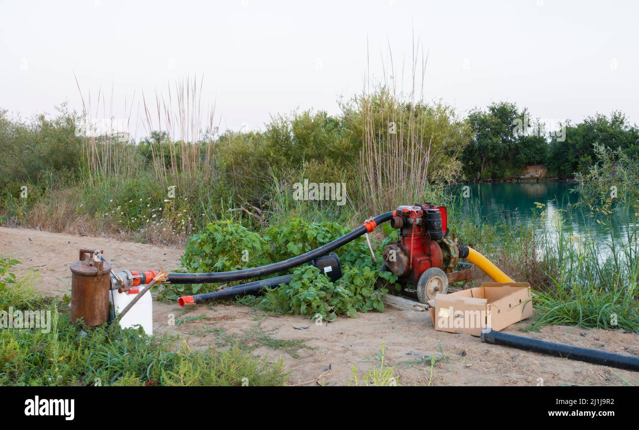 A red water engine drawing water from a river to irrigate a field ...