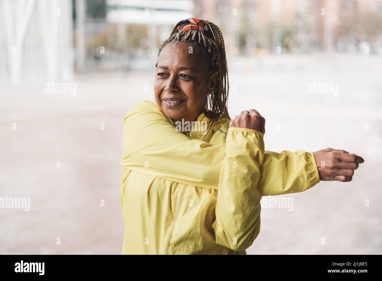 Senior african woman stretching during workout routine outdoor - Focus ...