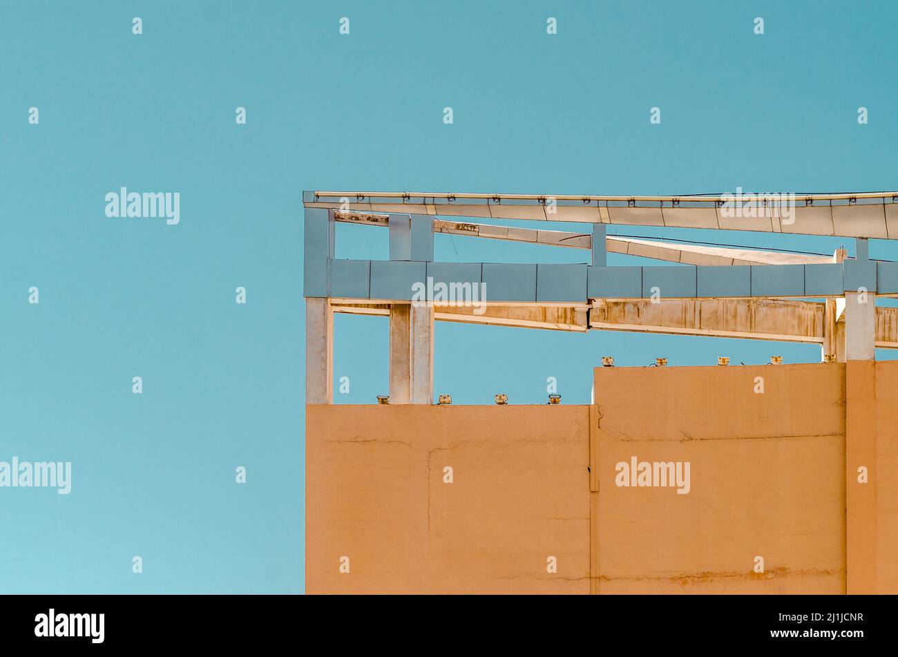 A house frame on the roof of a residential building against a blue sky ...