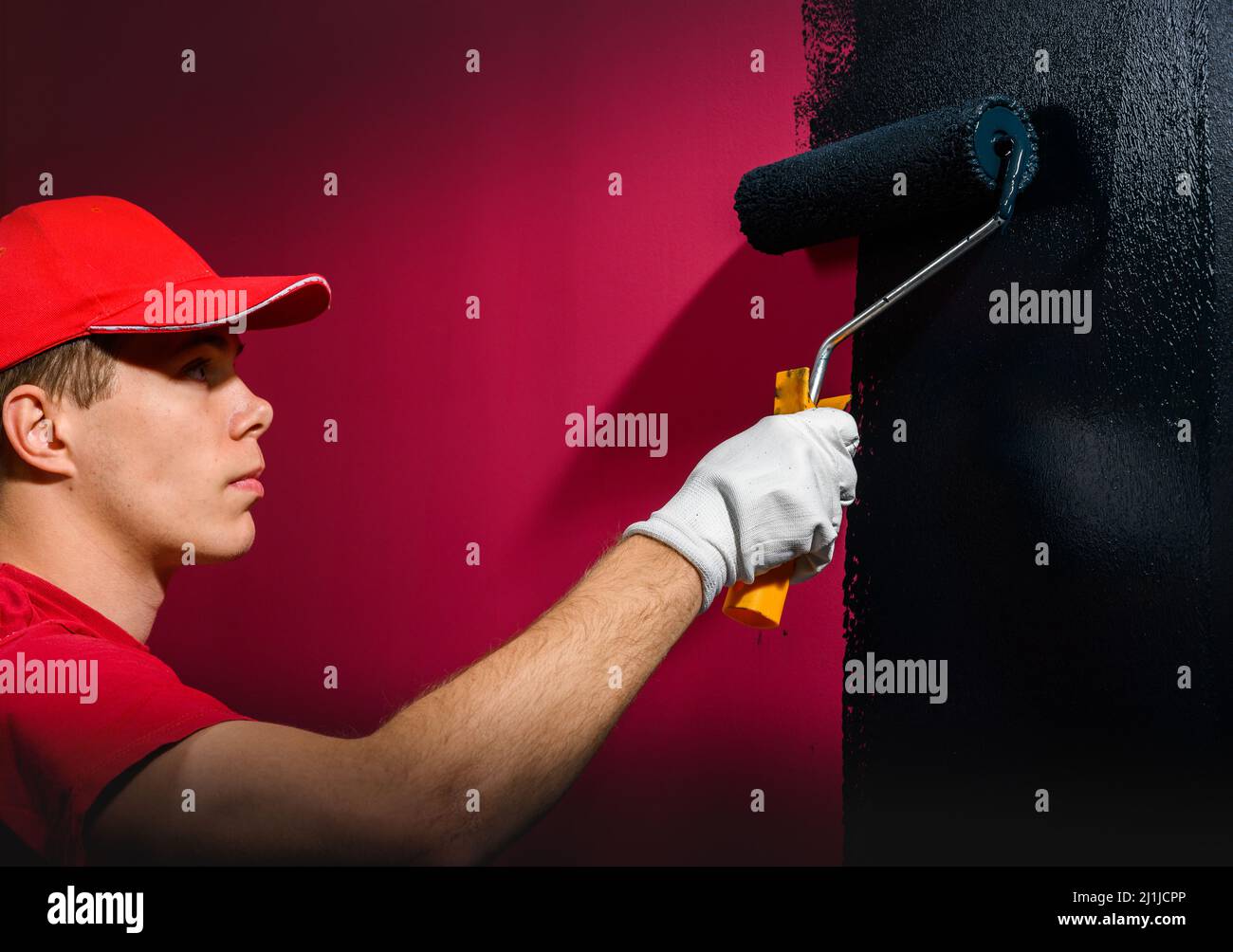 Man painting a wall. Painter in red overall painting wall in black ...