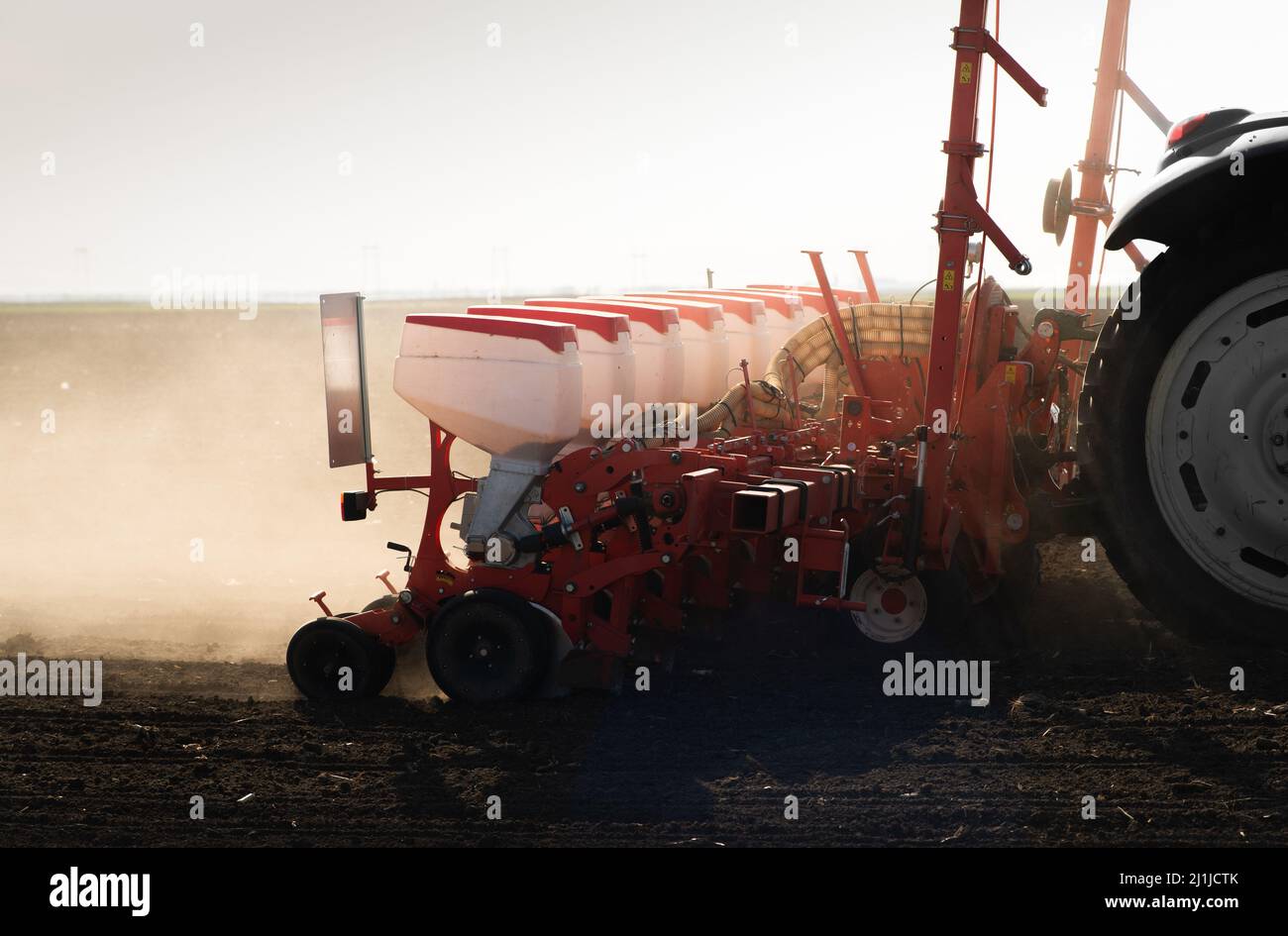 Farmer with tractor seeding - sowing crops at agricultural field ...
