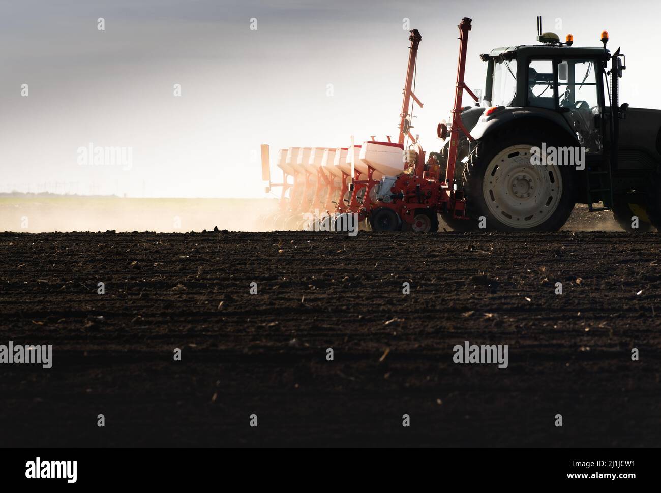 Farmer with tractor seeding - sowing crops at agricultural field ...