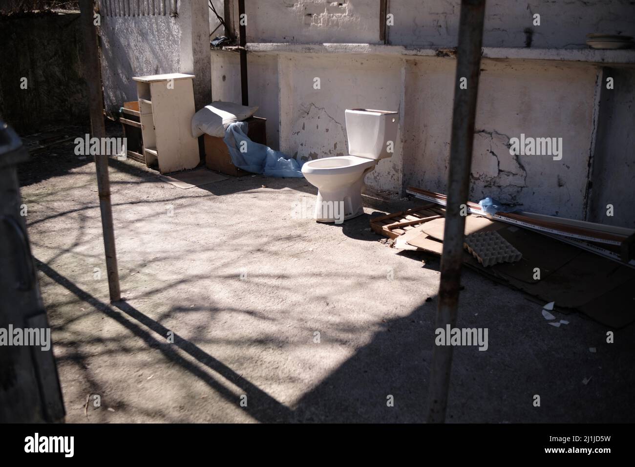 garbage from one old blue dirty toilet bowl lies on brown ground ...