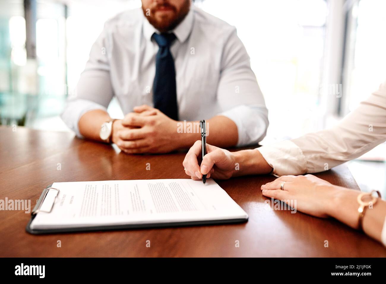 Sitting down to sign an agreement between two parties. Closeup shot of ...
