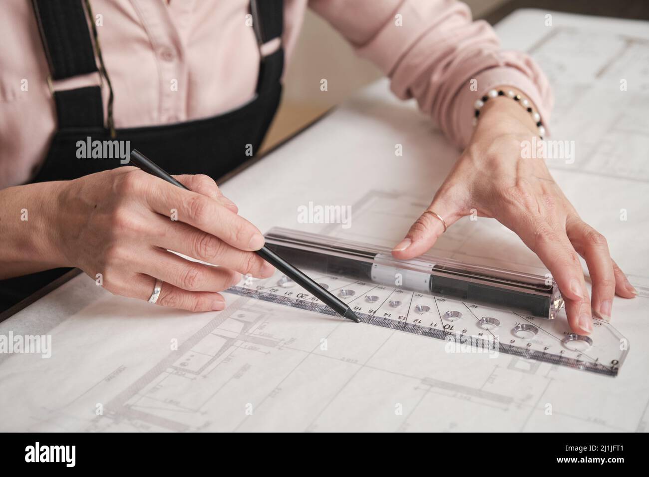 Close-up of unrecognizable female hands in ring using ruler and pencil ...