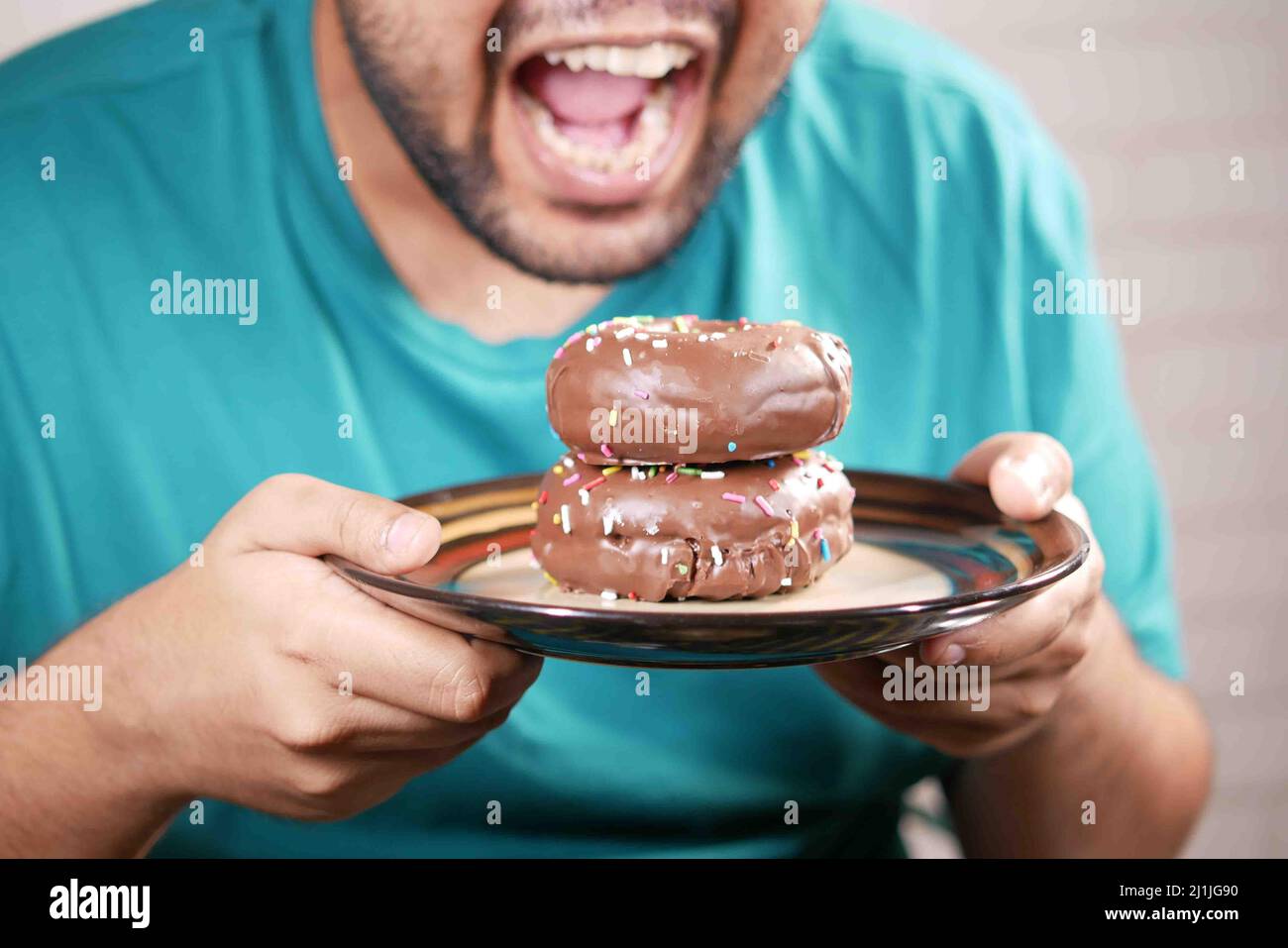 Young man eating donut hi-res stock photography and images - Alamy