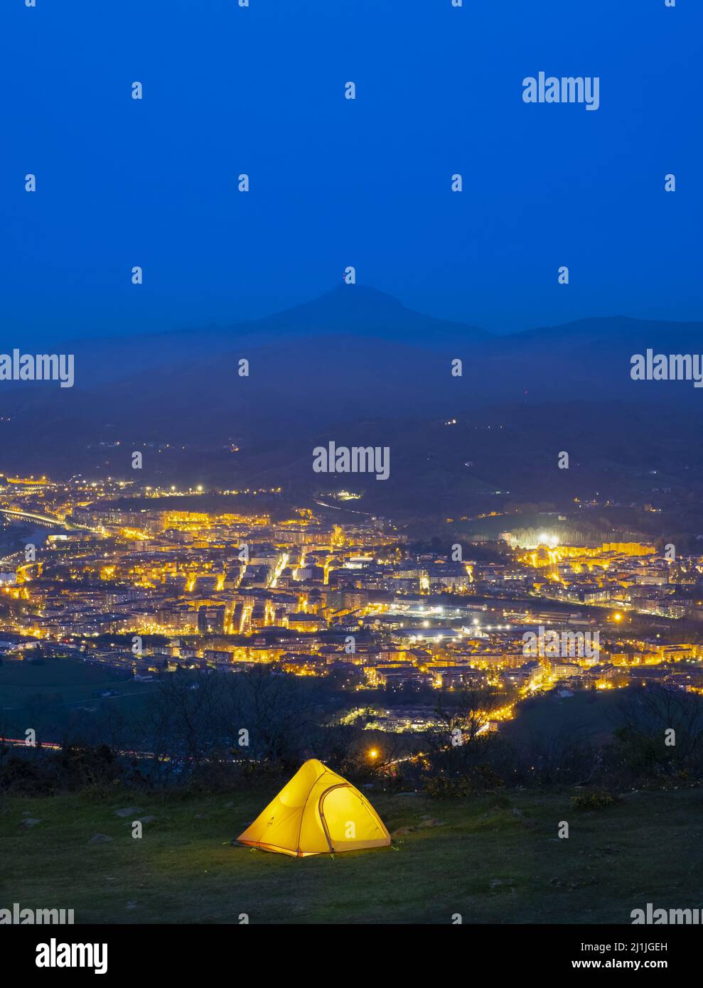 camping tent at night with the lights of the city in the background ...
