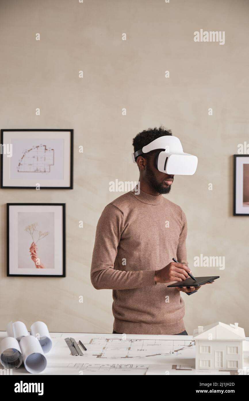 Modern young African-American architect in VR goggles standing in ...
