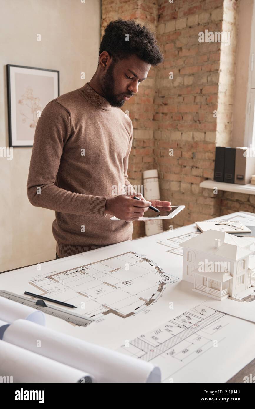Serious young African-American architectural engineer in brown sweater ...