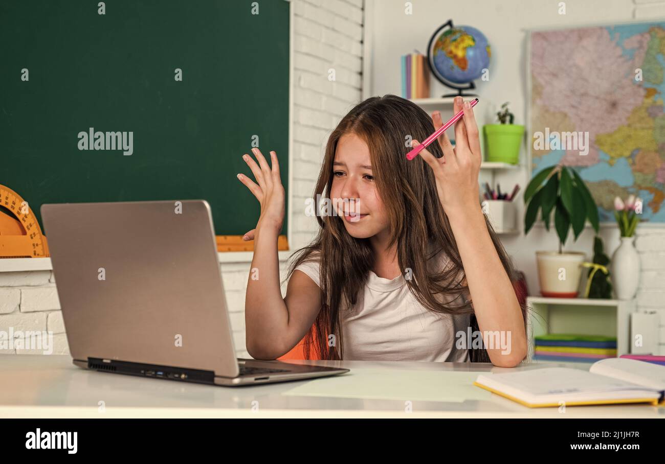 knowledge day. child pupil sit at table and use computer. girl is ...