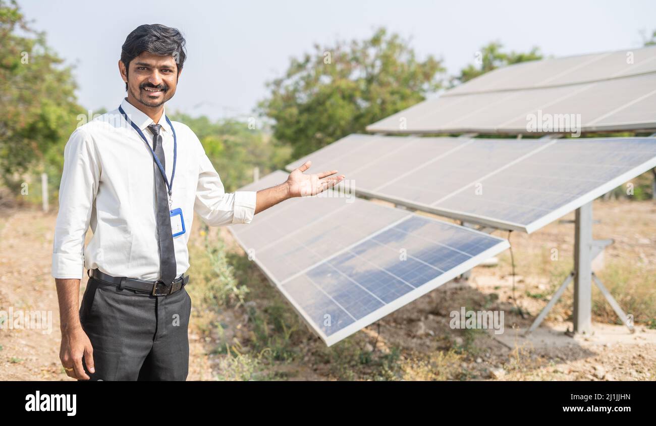happy smiling engineer showing solar power panels at farmland - concept ...
