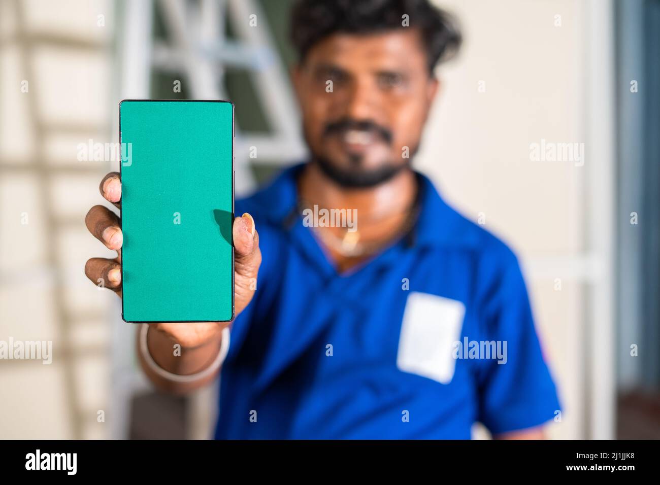 Aluminium worker showing green screen mobile phone by looking at camera ...