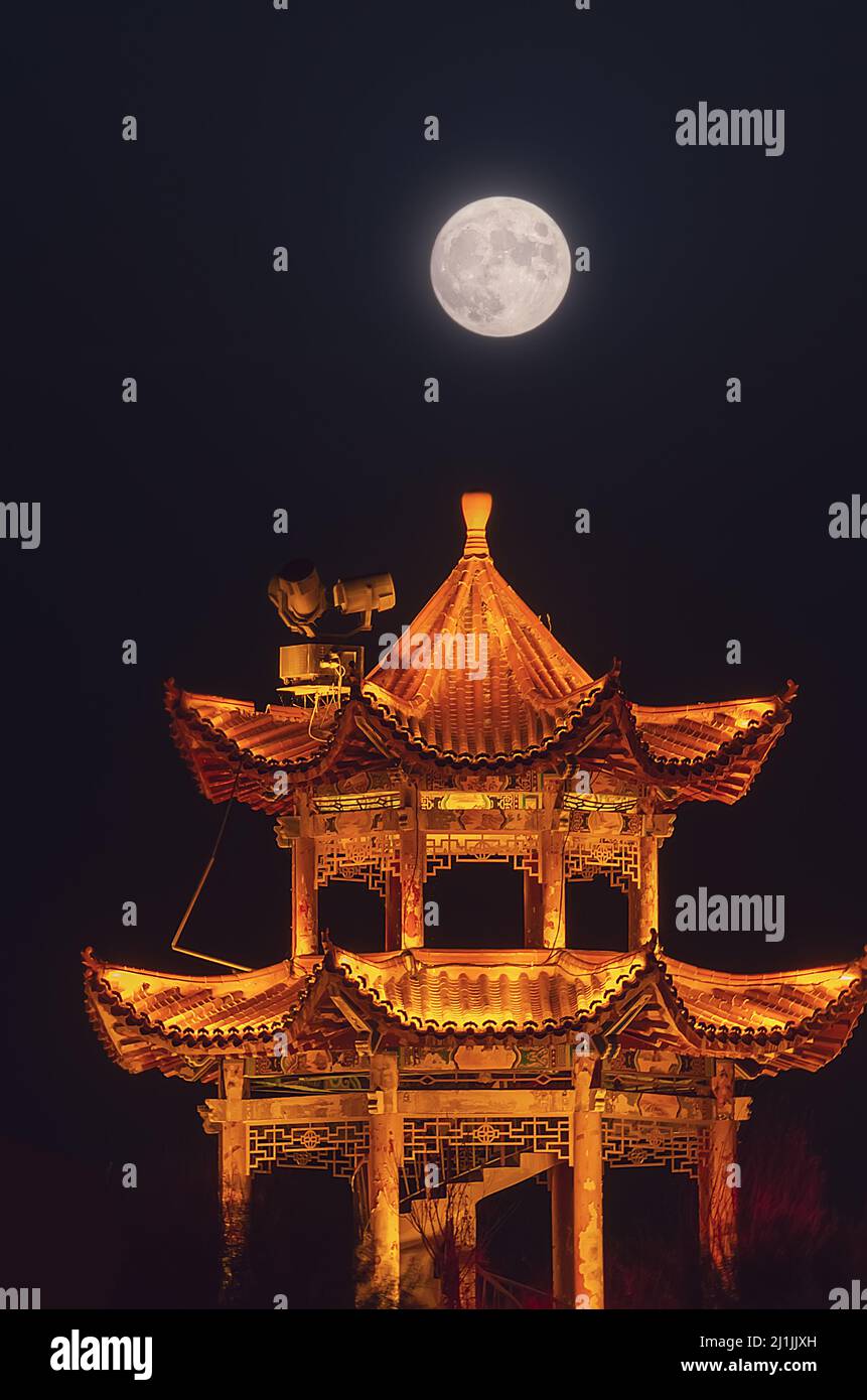 The golden Asian pagoda against the background of the full moon and ...