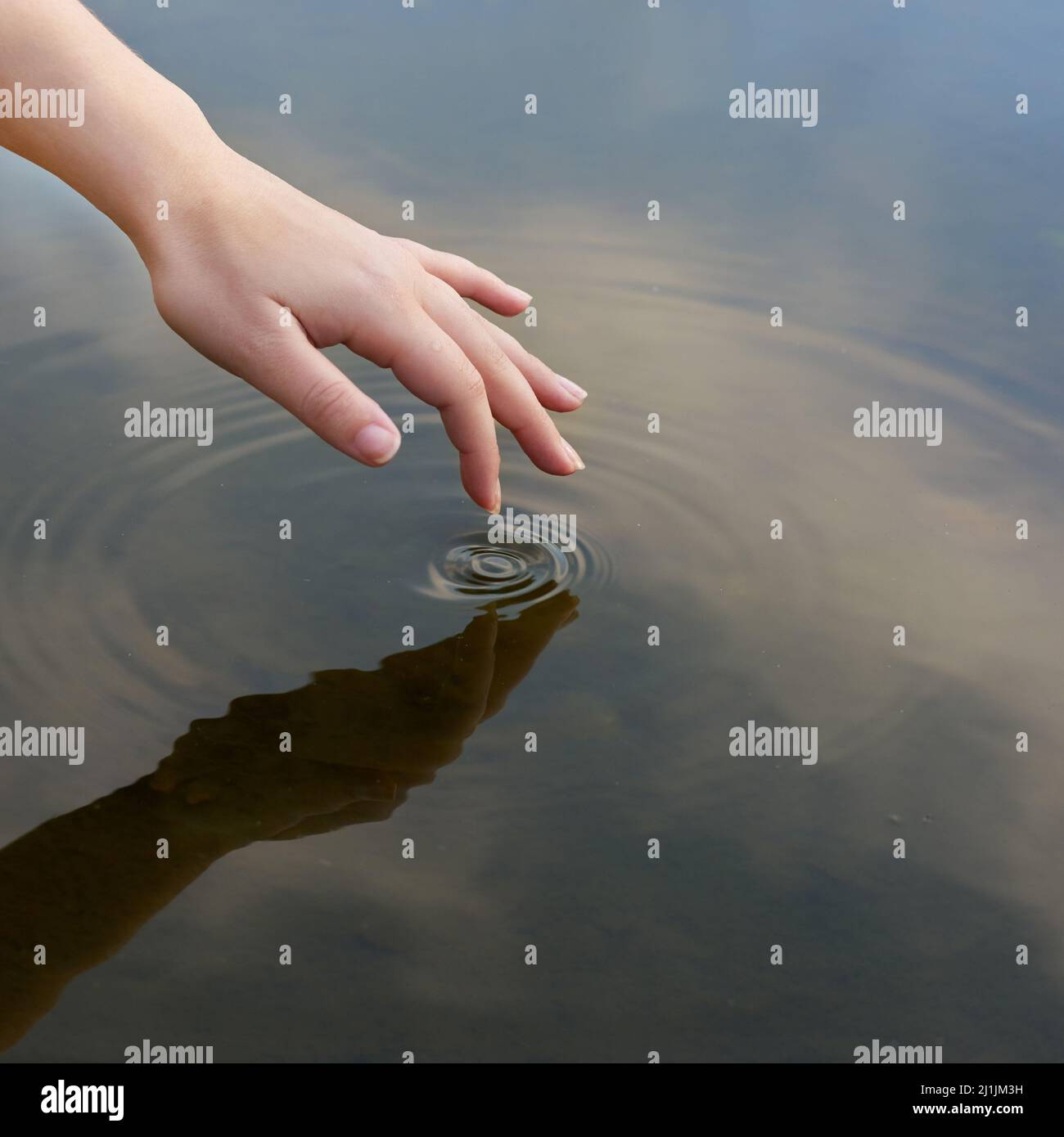 Patterns in a pond. Cropped shot of a finger touching water to form ...