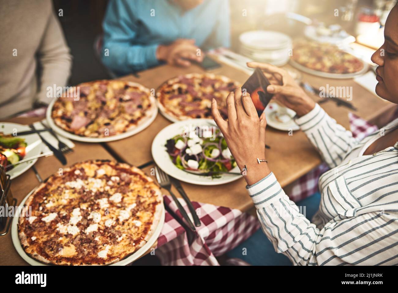 Pizza. Shot of a group of people seated at a table with plates of pizza ...