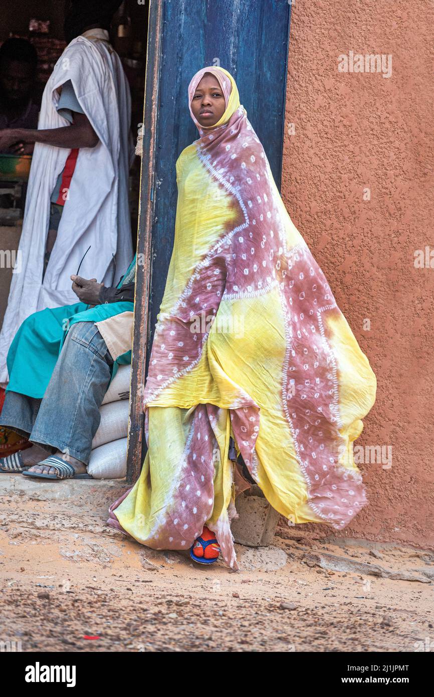 A girl with colorful boubou (traditional wear) in front of a shop ...