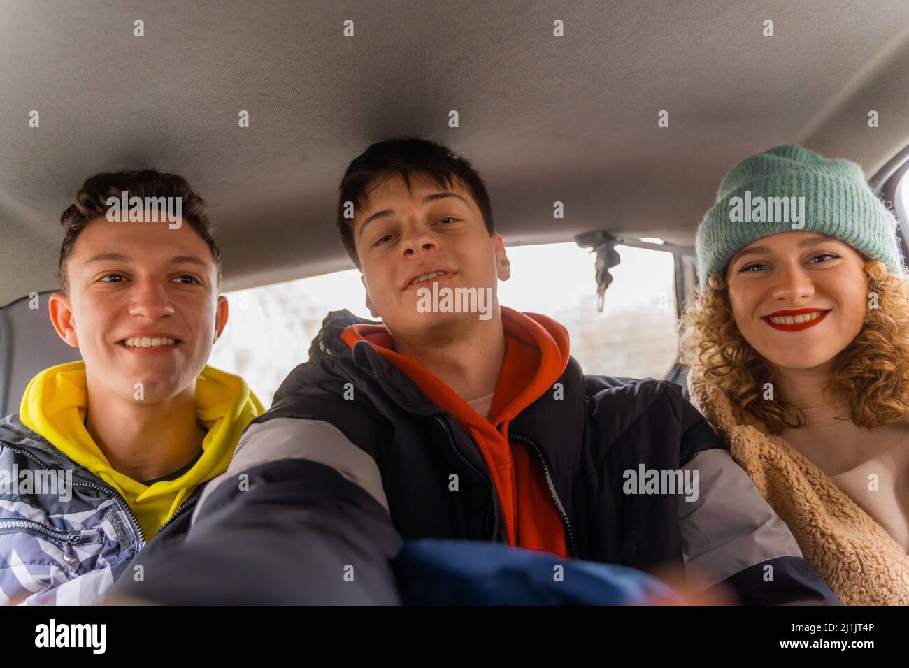 Amazing and beautiful young group of friends are taking a selfie in the car together while ...