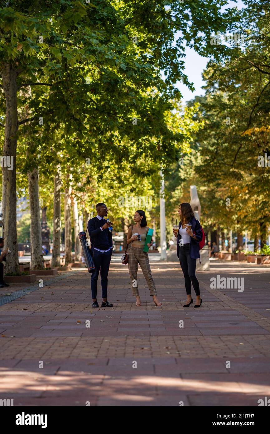 Three business people are standing while talking to each other and ...
