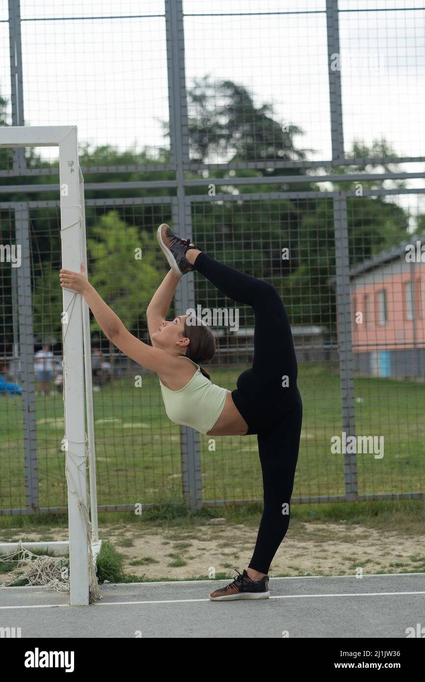 Adorable and sweet girl is stretching and bending her leg while holding ...