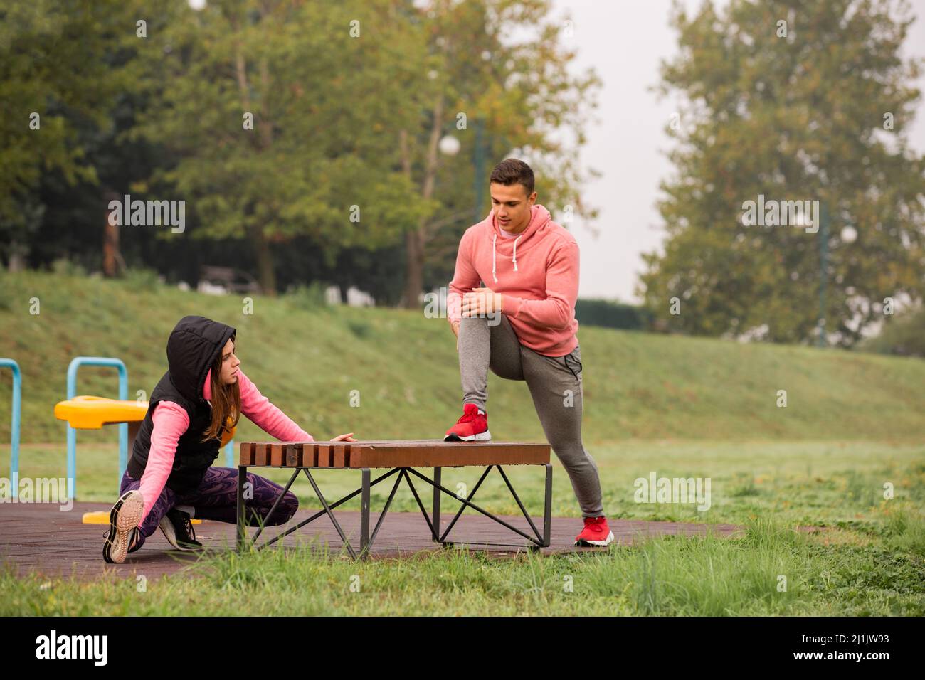 Attractive and amazing friends are stretching together on the bench ...