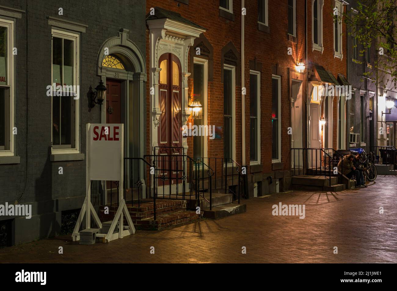 a photo of lighted houses at night with a for sale sign in the front of ...
