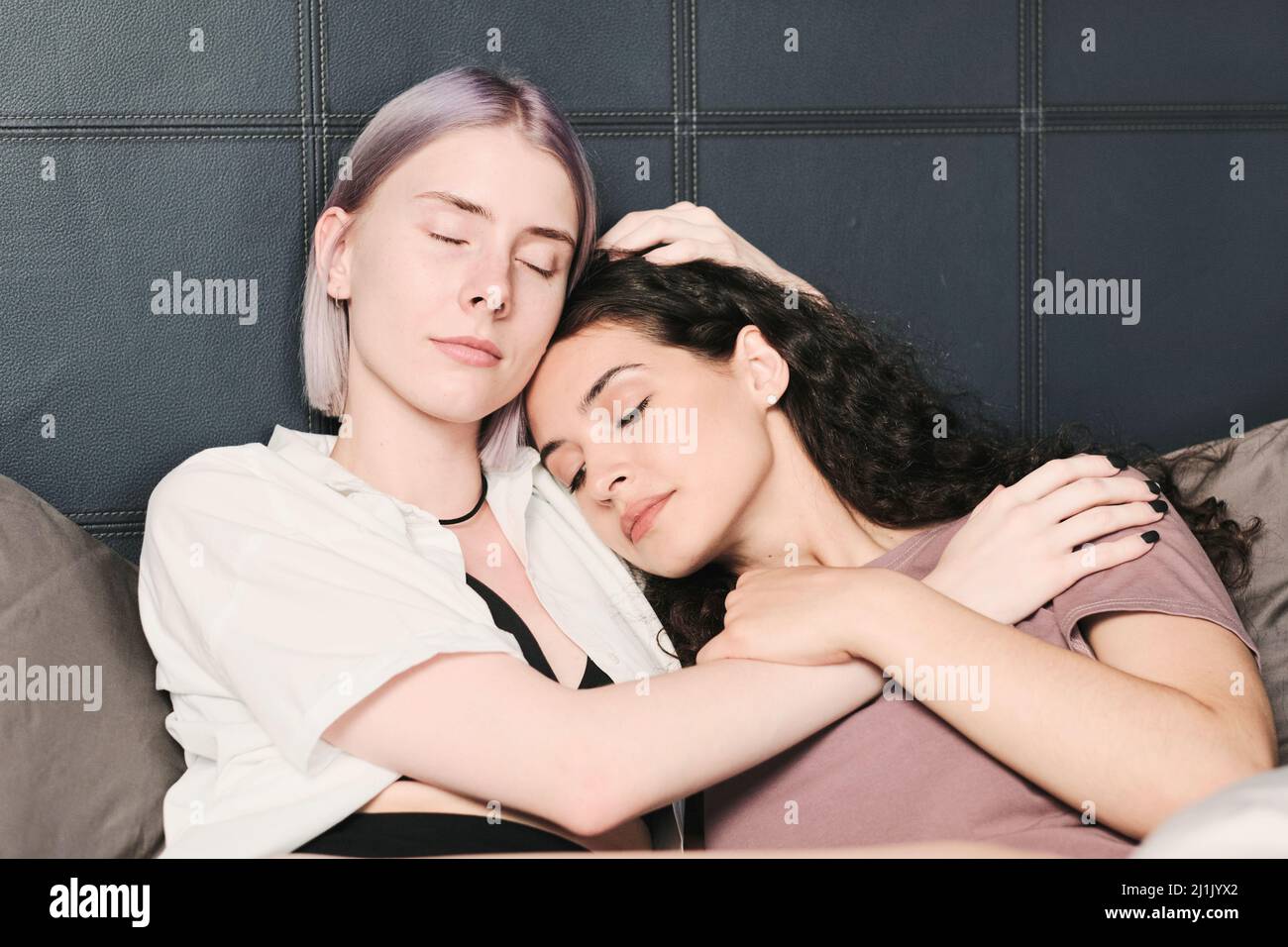 Calm loving young woman with closed eyes hugging girlfriend while they ...