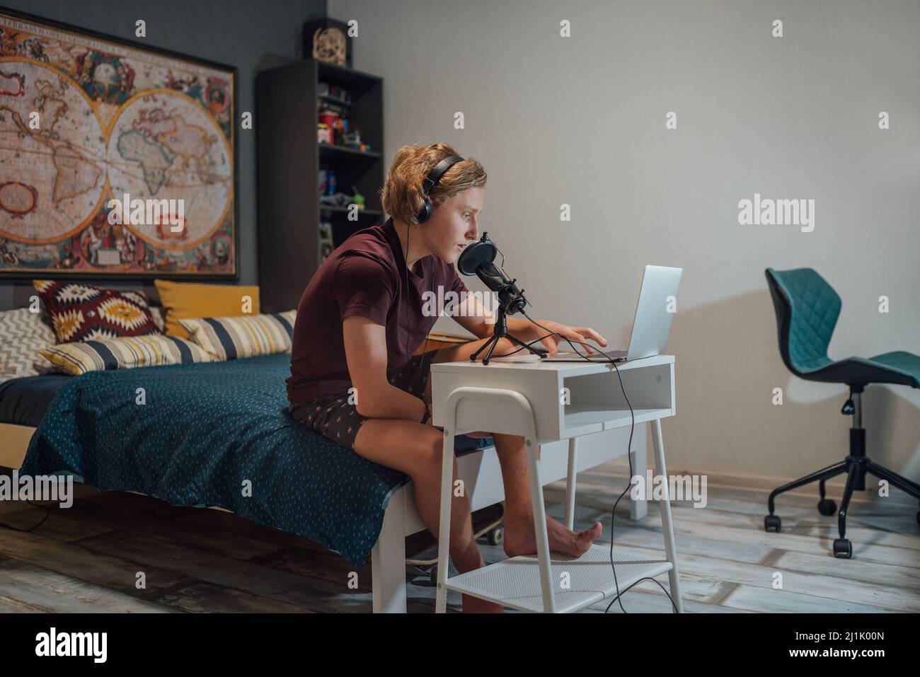 Portrait photo of a young teenage boy in headphones recording voice or ...