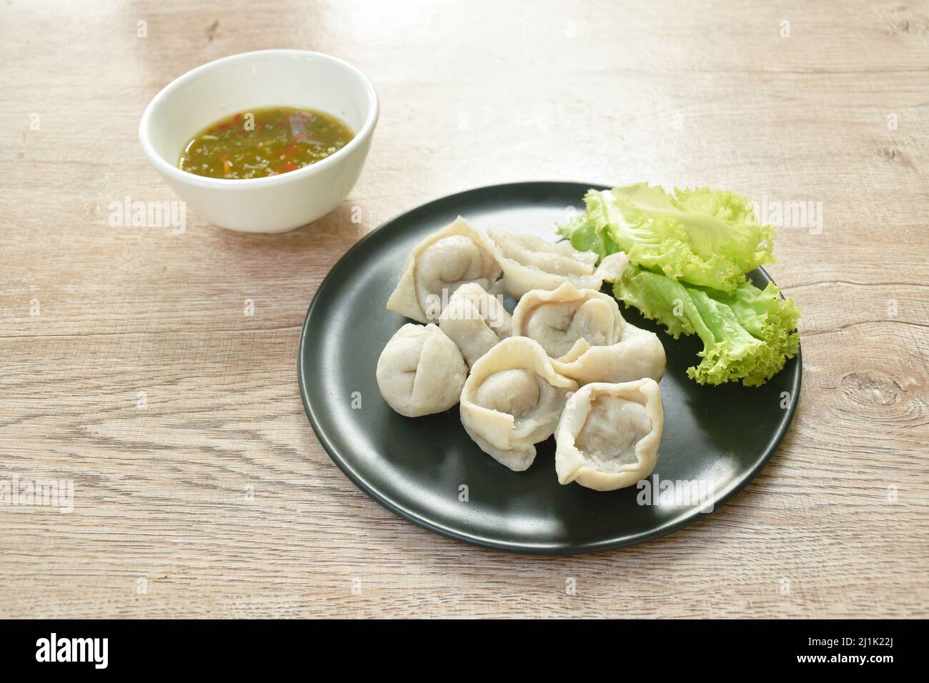 steamed fish dumpling with lettuce on plate dipping spicy and sour ...