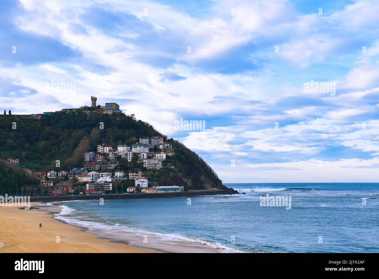 The cloudy blue sky over the sea and small coastal town of Bakio ...