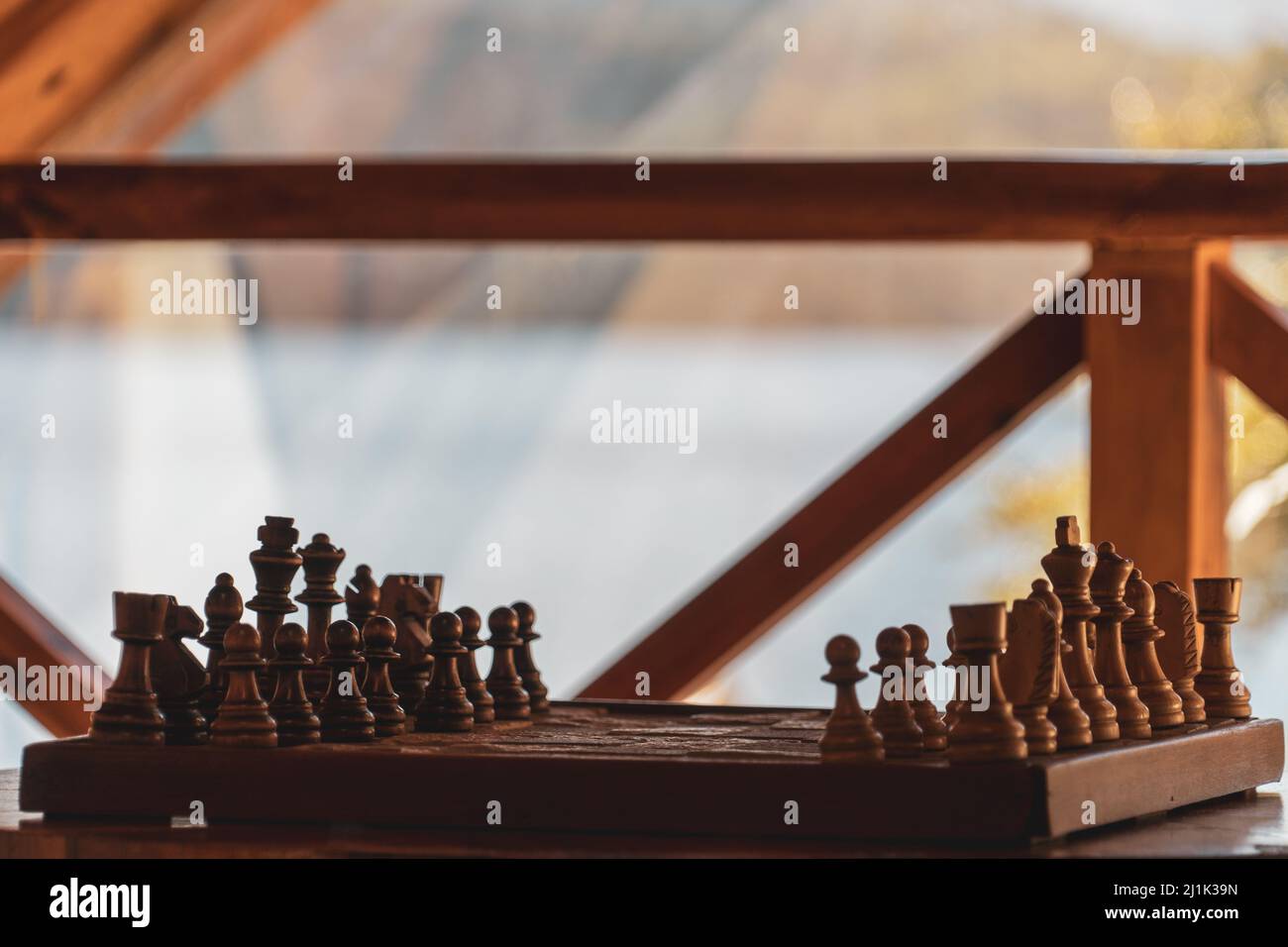 A chess board with wooden chess pieces with the blurred background of a ...