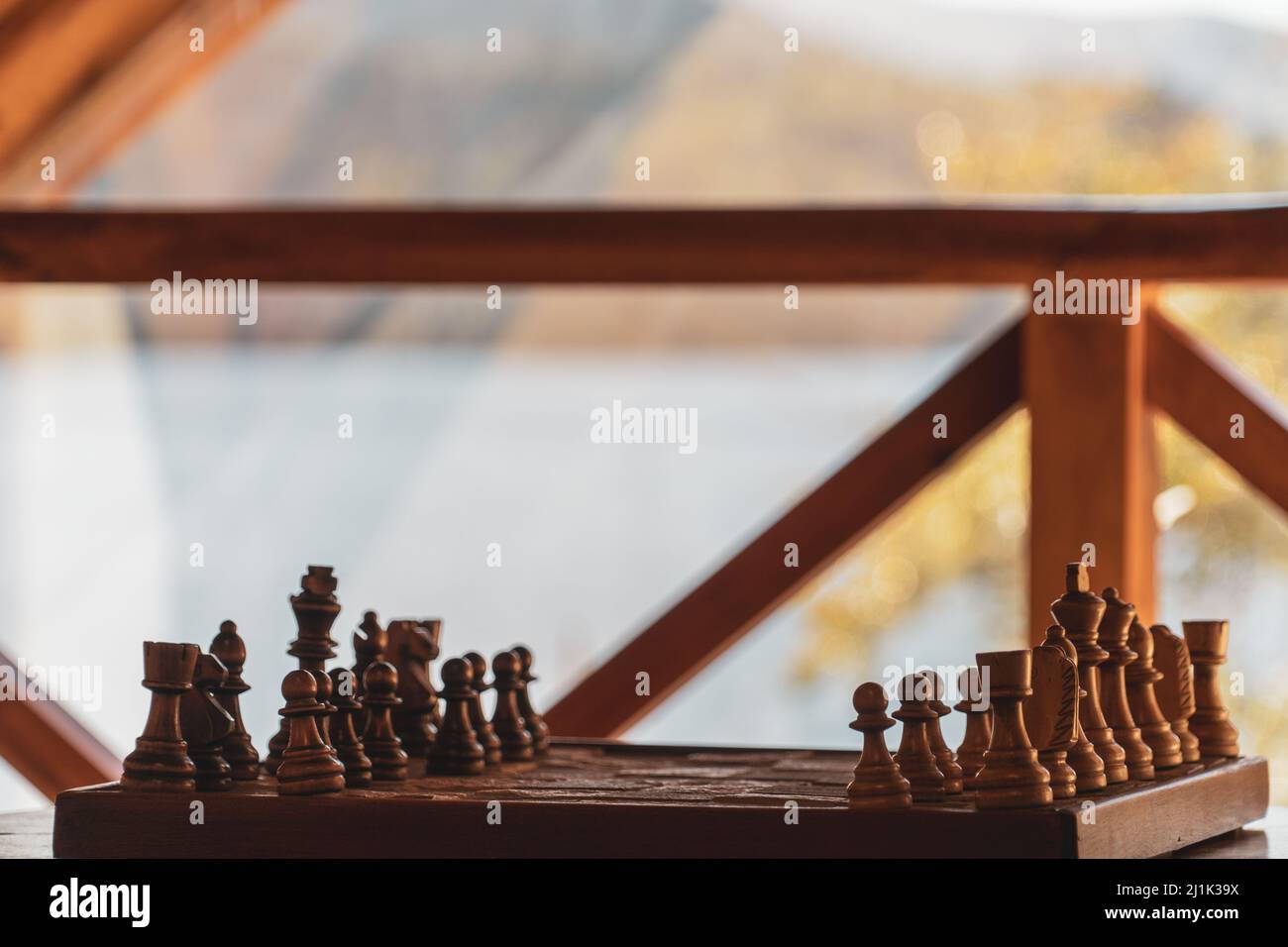 A chess board with wooden chess pieces with the blurred background of a ...
