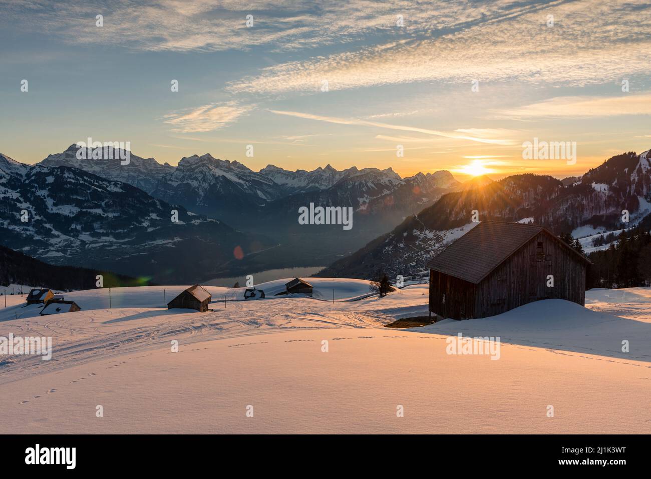 Snow-covered mountain meadows with hay huts in front of the panorama of ...