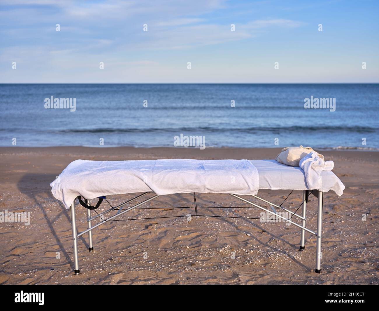 A massage table placed on the sand of a beach with the sea in the ...