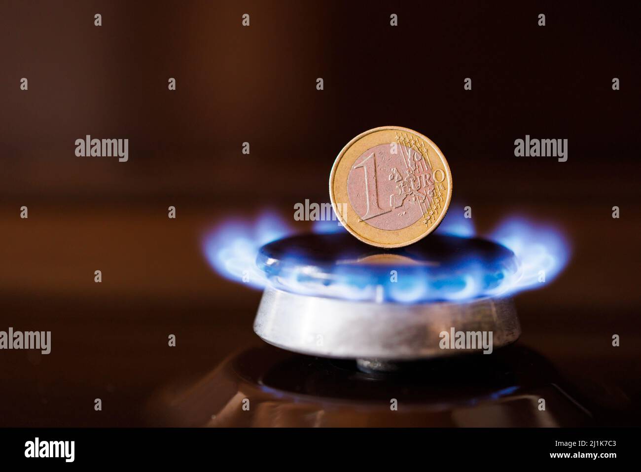 gas stove burner with one euro coin standing vertically on top, burning ...