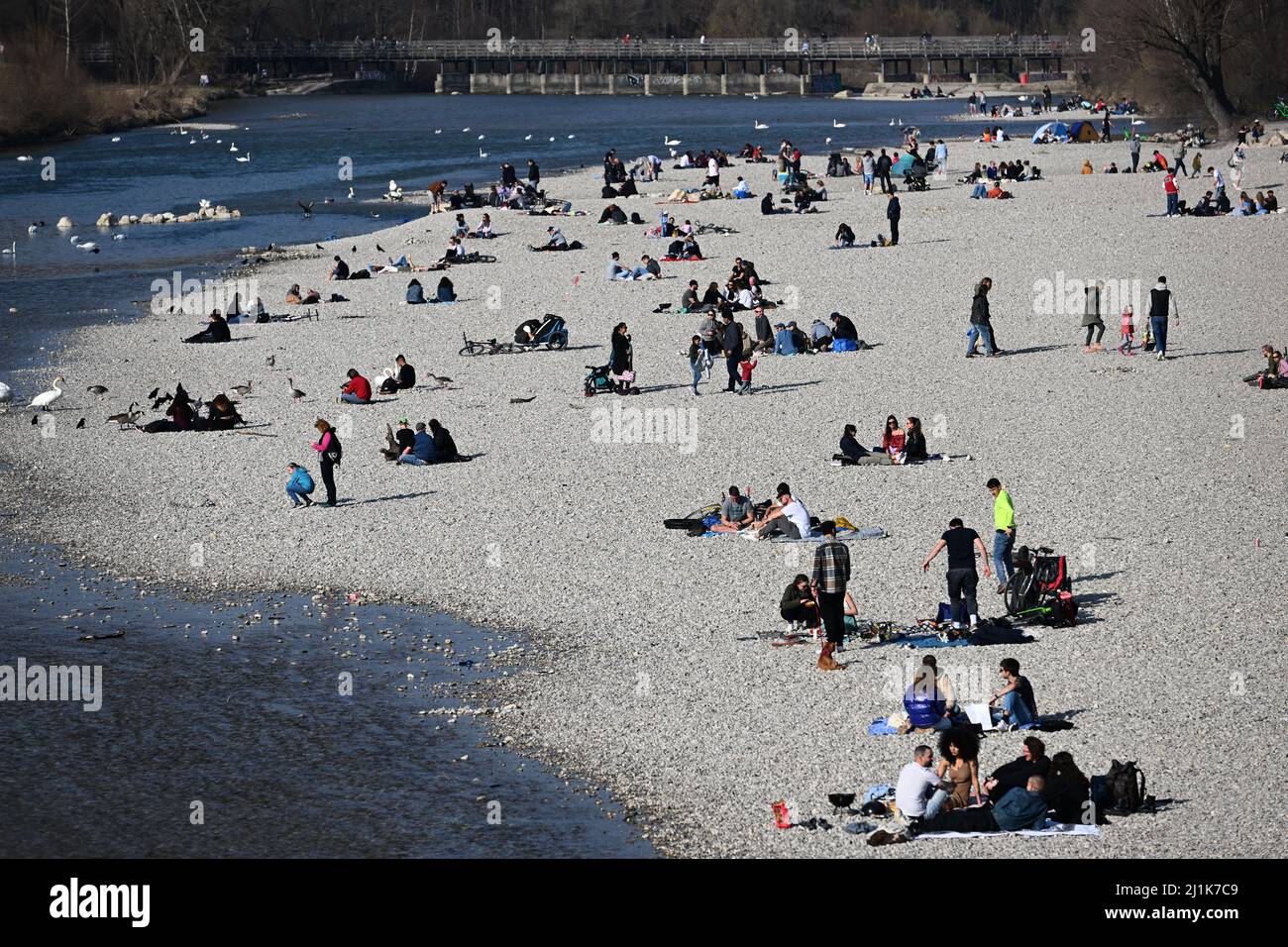 Munich, Germany. 26th Mar, 2022. Numerous sunbathers sit on the gravel ...