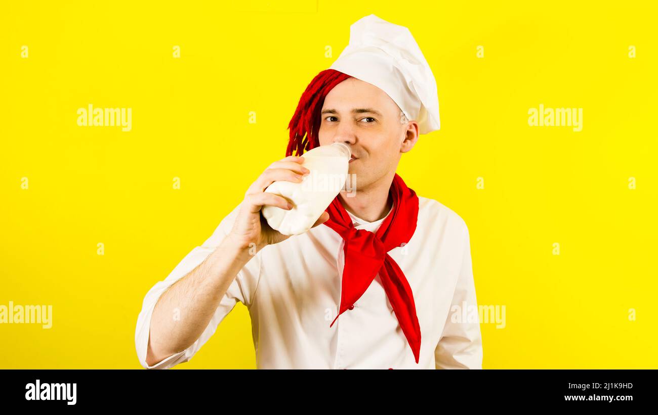 Man with red dreadlocks with bottle milk. Confident young cook in white ...