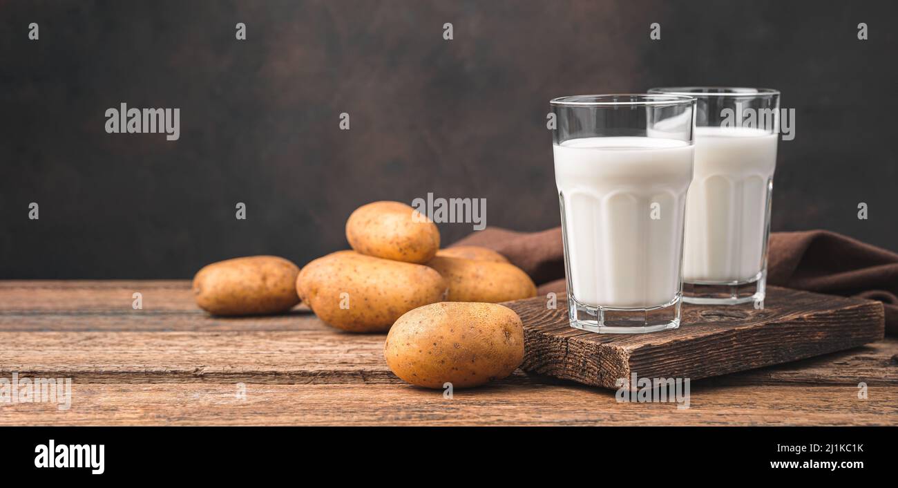 Potato milk in two glasses on the background of potatoes. An ...