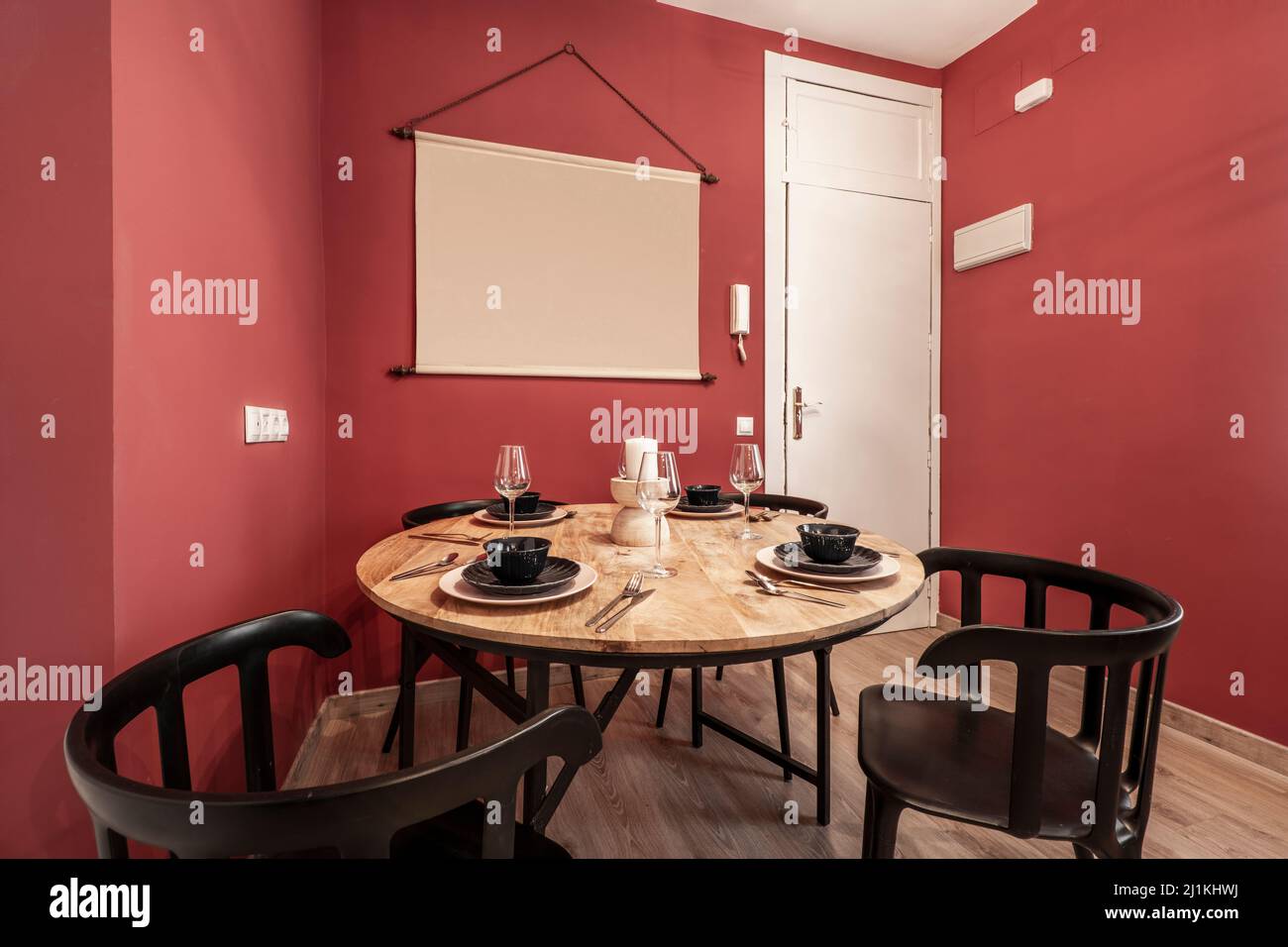 Apartment with round wooden dining table, food service, black chairs ...