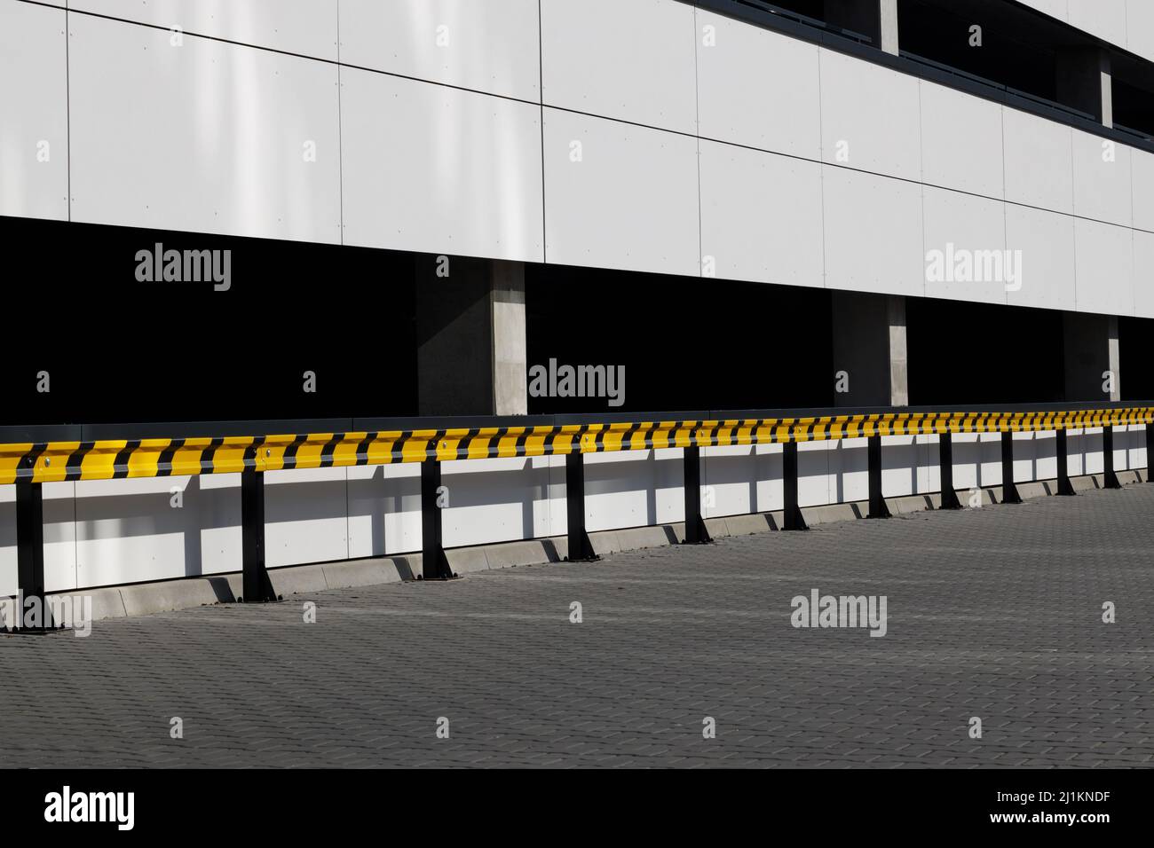 Yellow and black guardrails outside building, parking lot Stock Photo ...