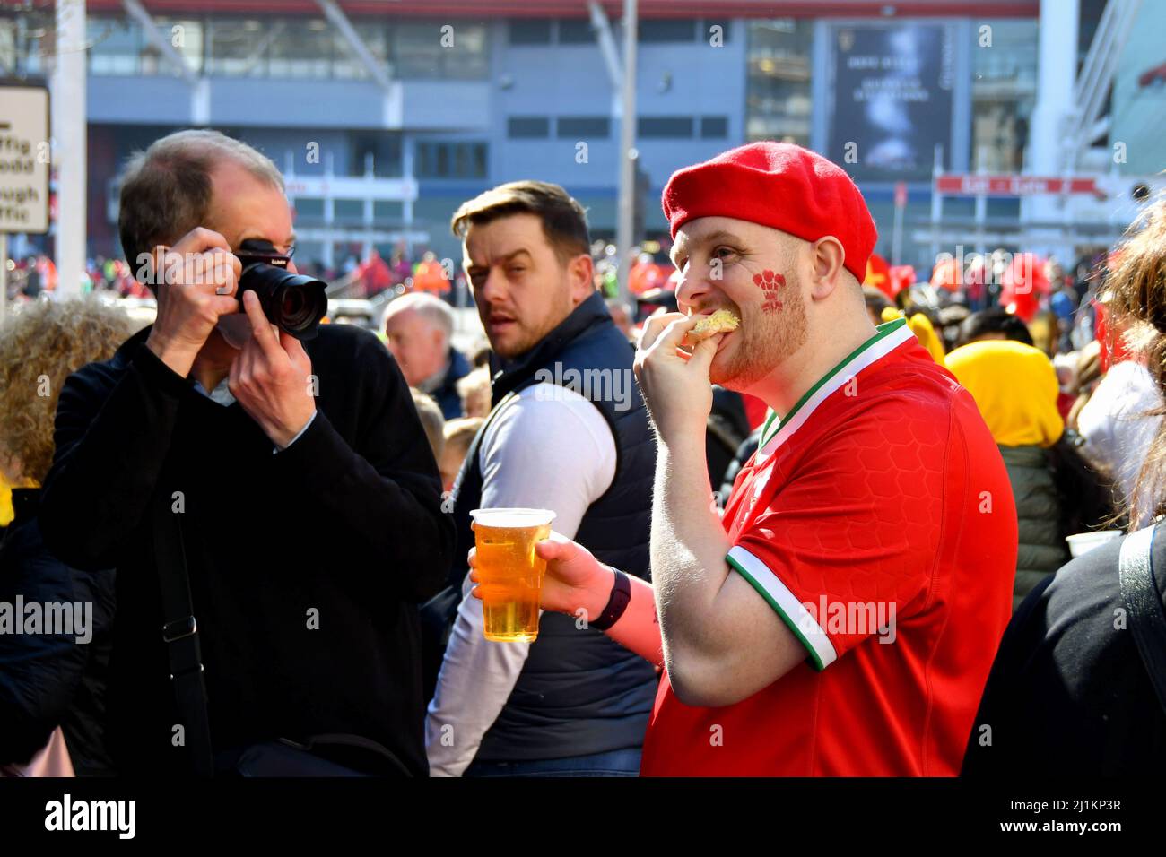 Cardiff, Wales - March 2022: Rugby fan eating a snack and holding a ...