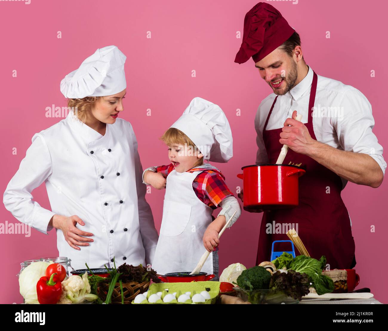Little son and parents in chef hats in kitchen. Family cooking together ...