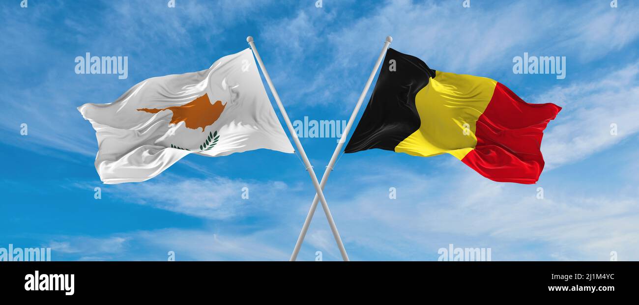 two crossed flags Cyprus and Belgium waving in wind at cloudy sky ...