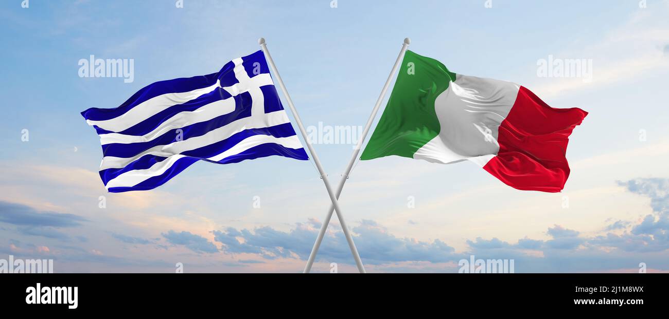 two crossed flags Greece and Italy waving in wind at cloudy sky ...