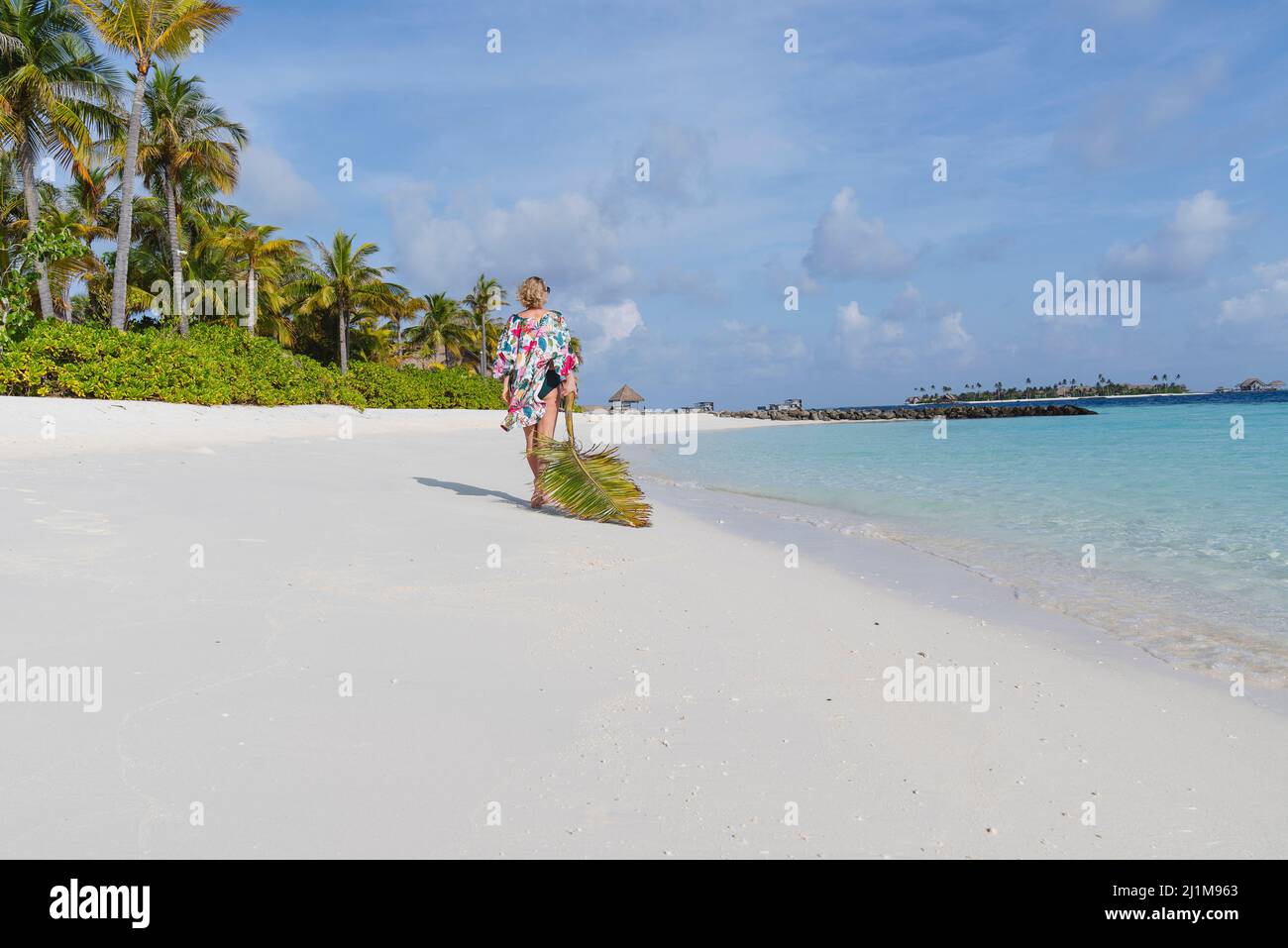 A woman on a beautiful beach with a palm tree branch Stock Photo - Alamy