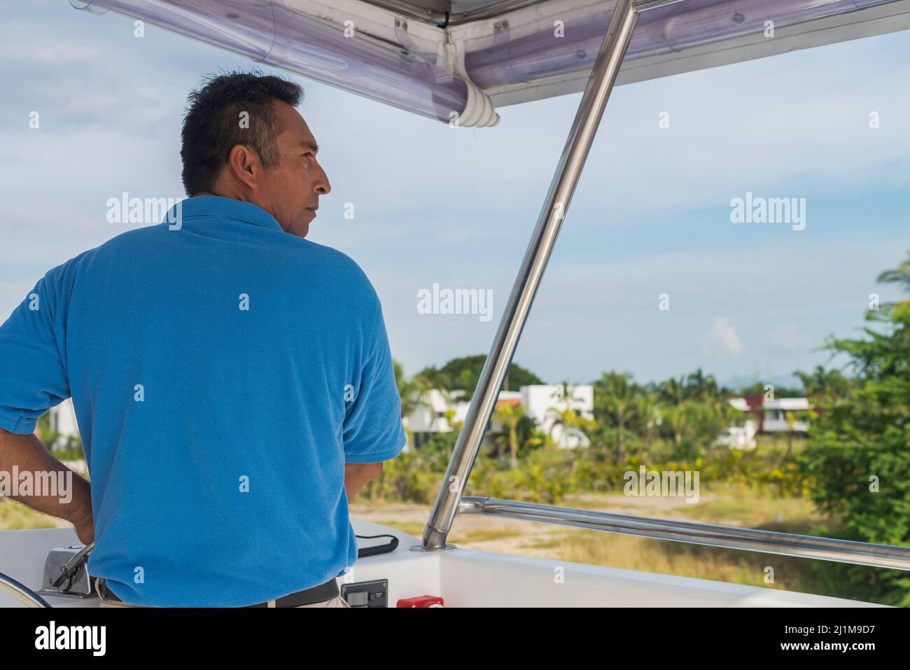Latin captain steering the boat approaching to the dock Stock Photo - Alamy