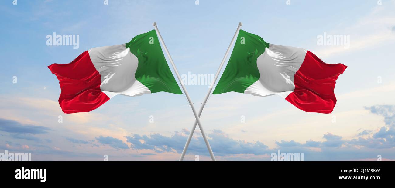 two crossed flags of Italy waving in wind at cloudy sky. Concept of ...