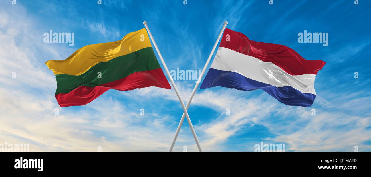 two crossed flags LITHUANIA and Netherland waving in wind at cloudy sky ...